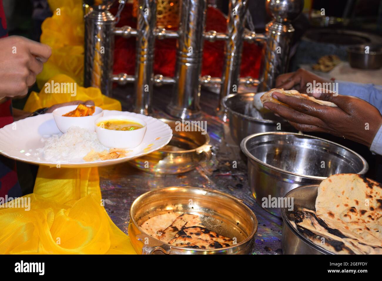 Hand of Indian man carrying Tandoori Roti in his plate from a large pot ...
