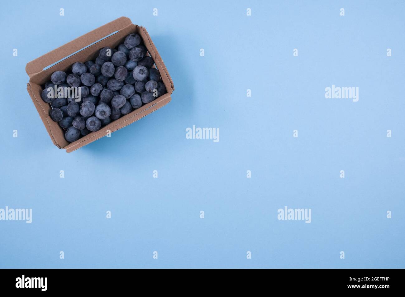 Top view of delicious blueberries in a paper box isolated on a blue ...