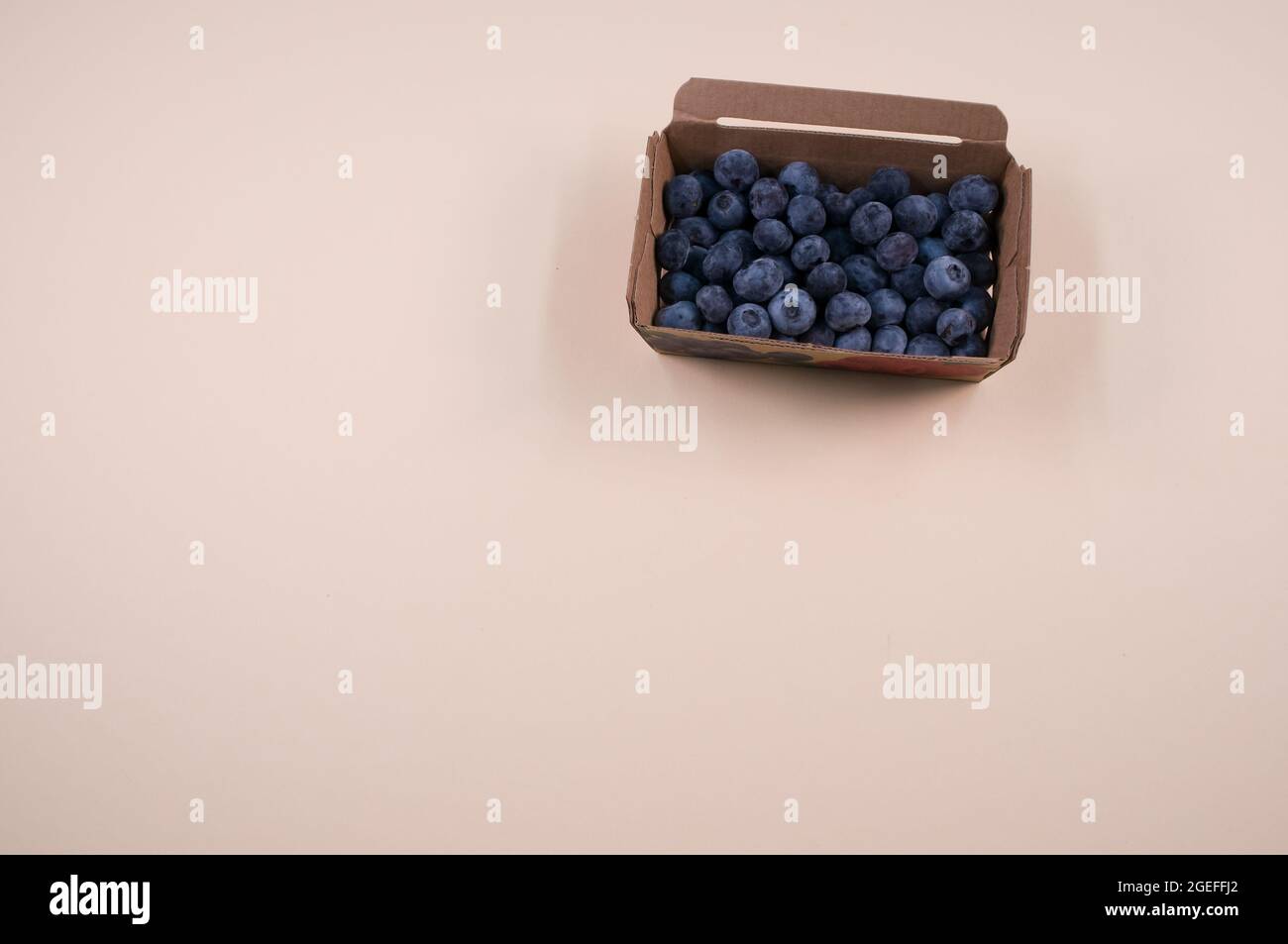 Top view of delicious blueberries in a paper box isolated on a beige ...