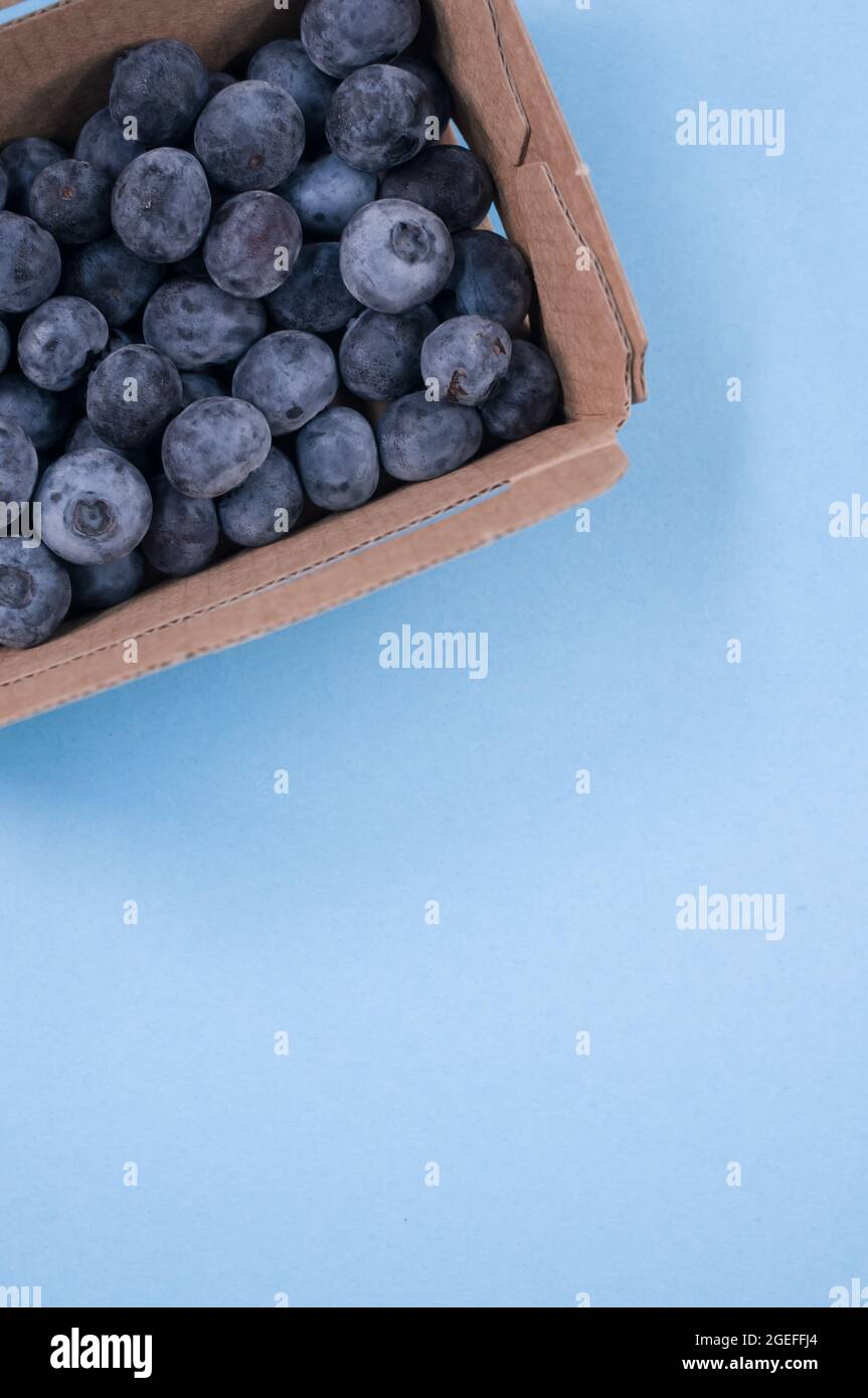 Top view of delicious blueberries in a paper box isolated on a blue ...