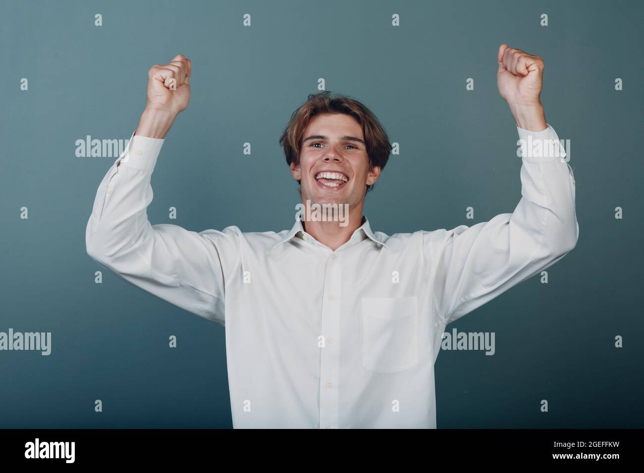 Young man winner joy and throws his hands up raised arms in the air ...