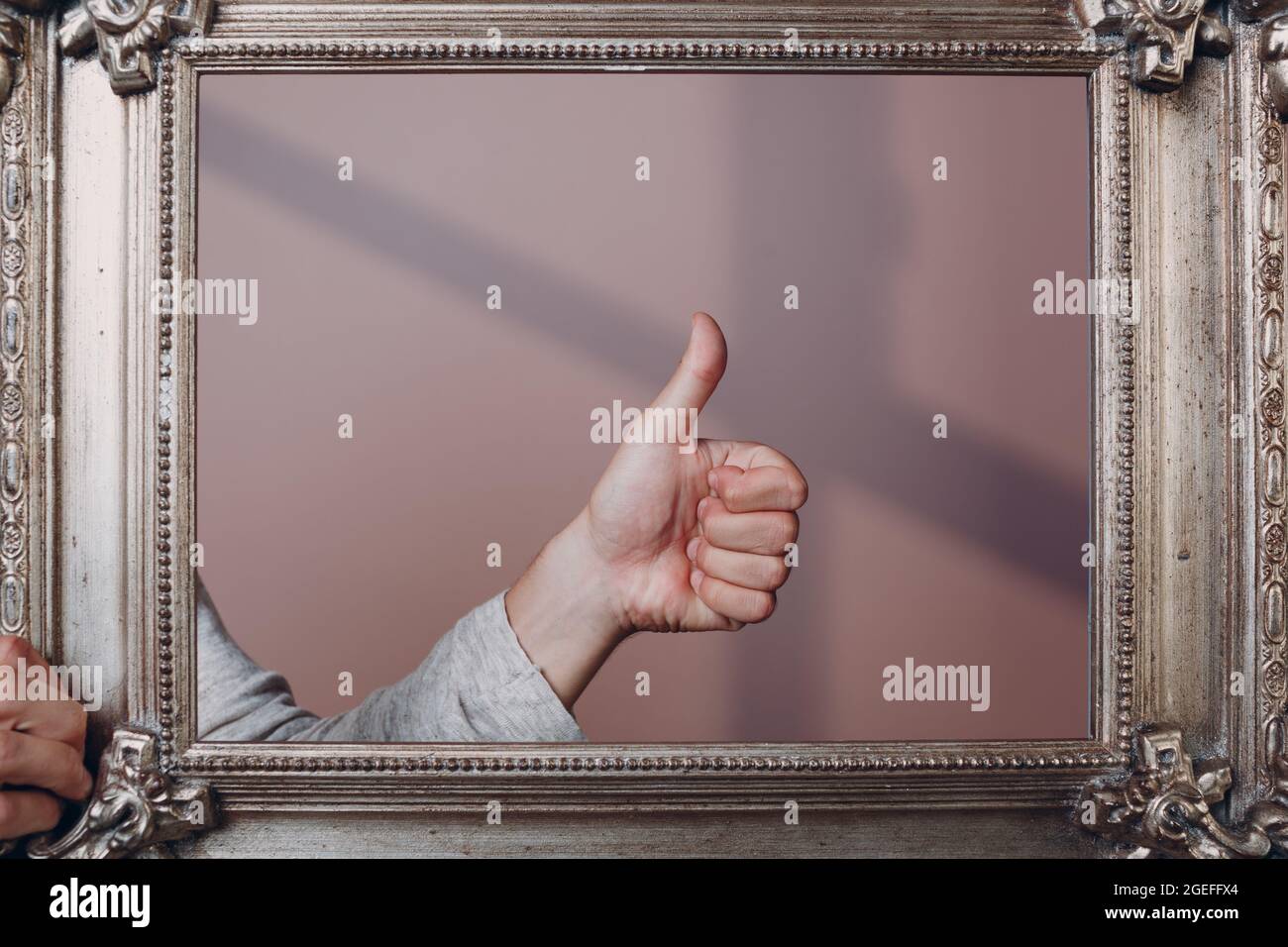 Thumbs up on gilded picture frame pink background Stock Photo - Alamy