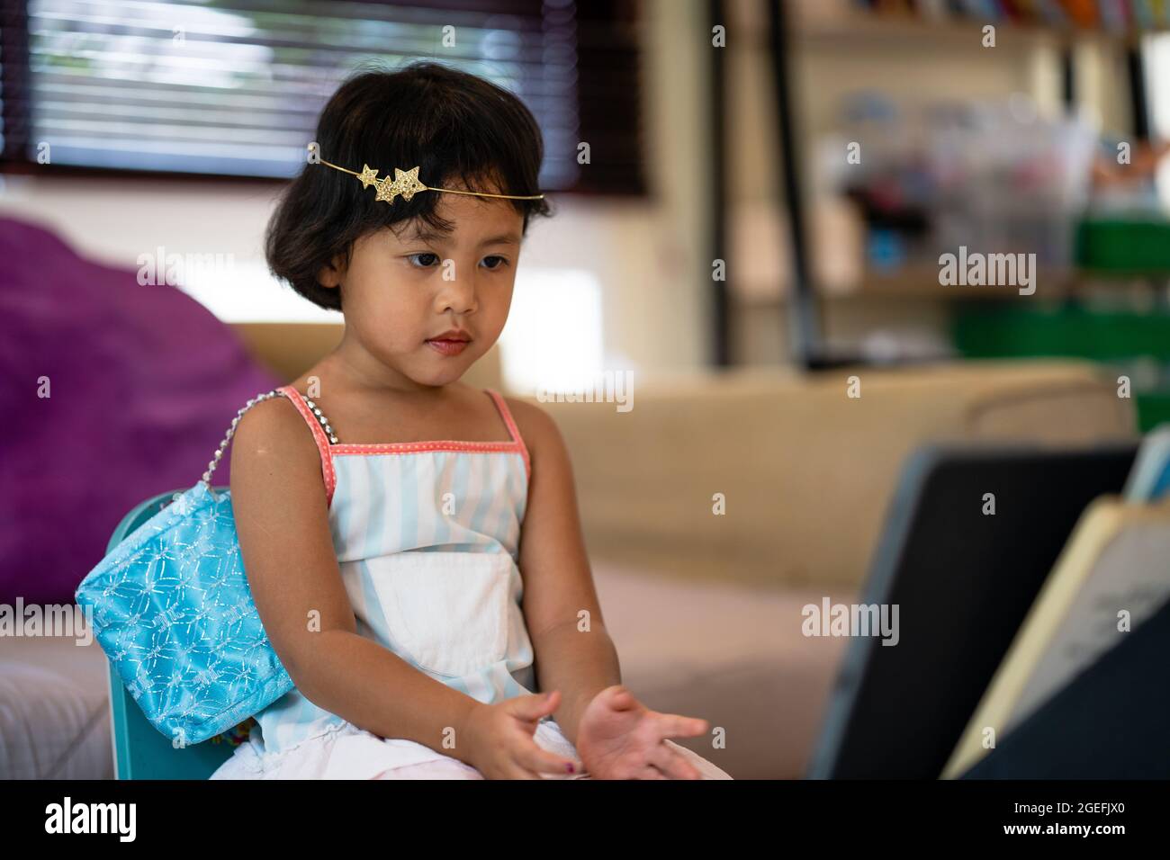 Closeup shot of a Southeast Asian little kid sitting on a chair Stock ...