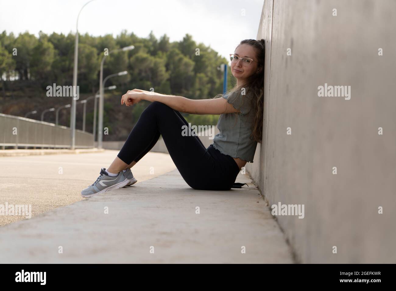 Closeup of a girl sitting on the pavement and leaning on the wall Stock ...