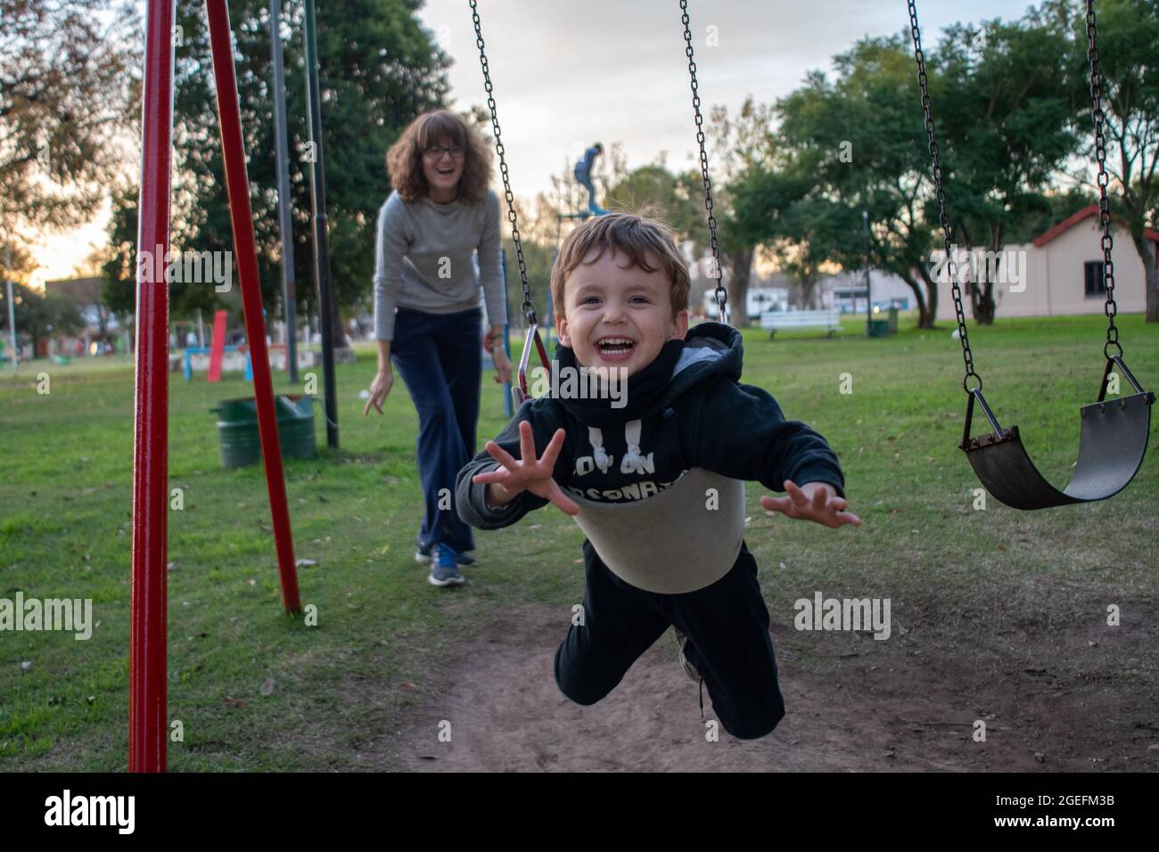Cute happy male child being pushed by his mother on a swing Stock Photo ...