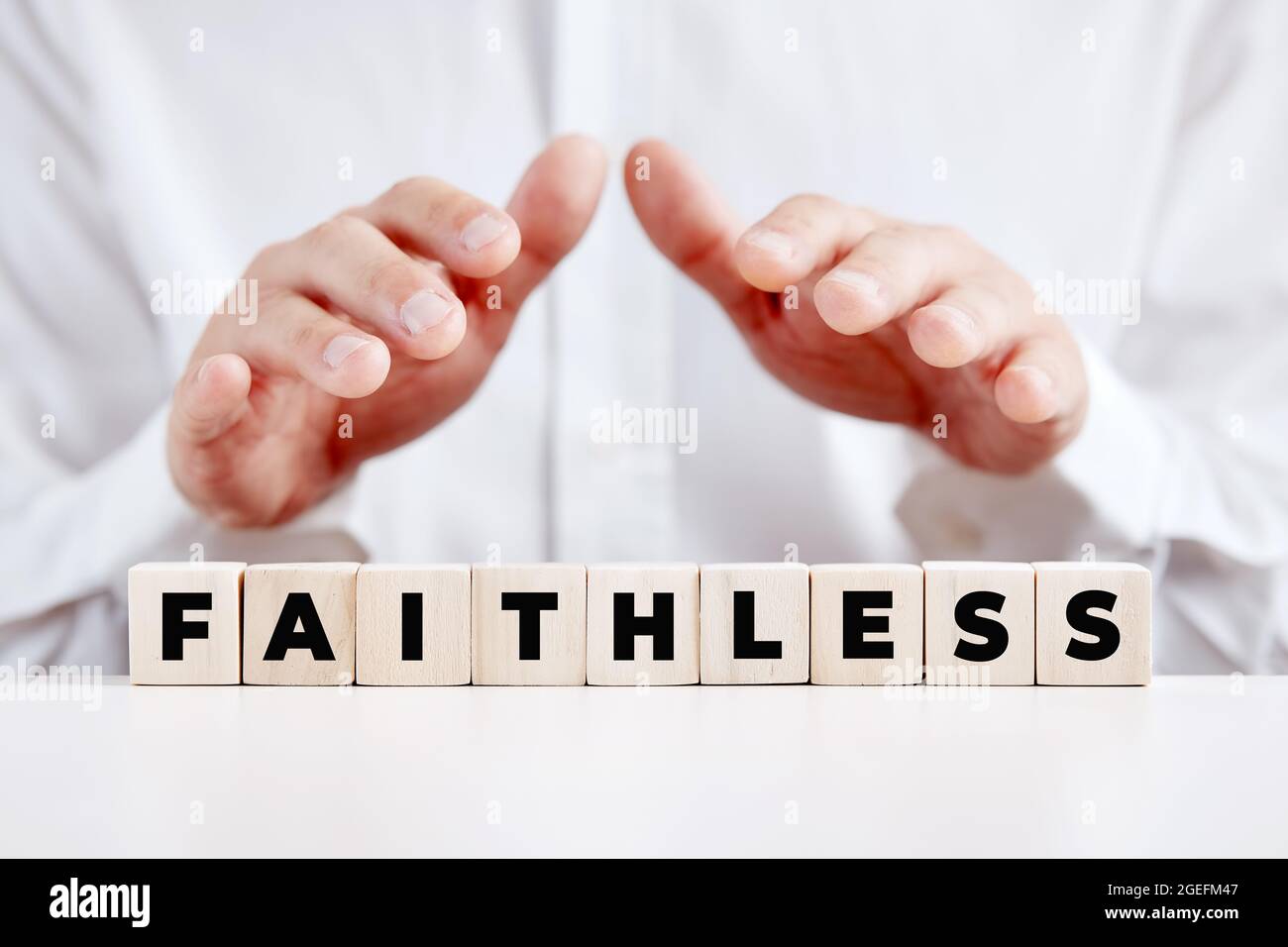 Man holding his hands over the wooden cubes with the word faithless ...
