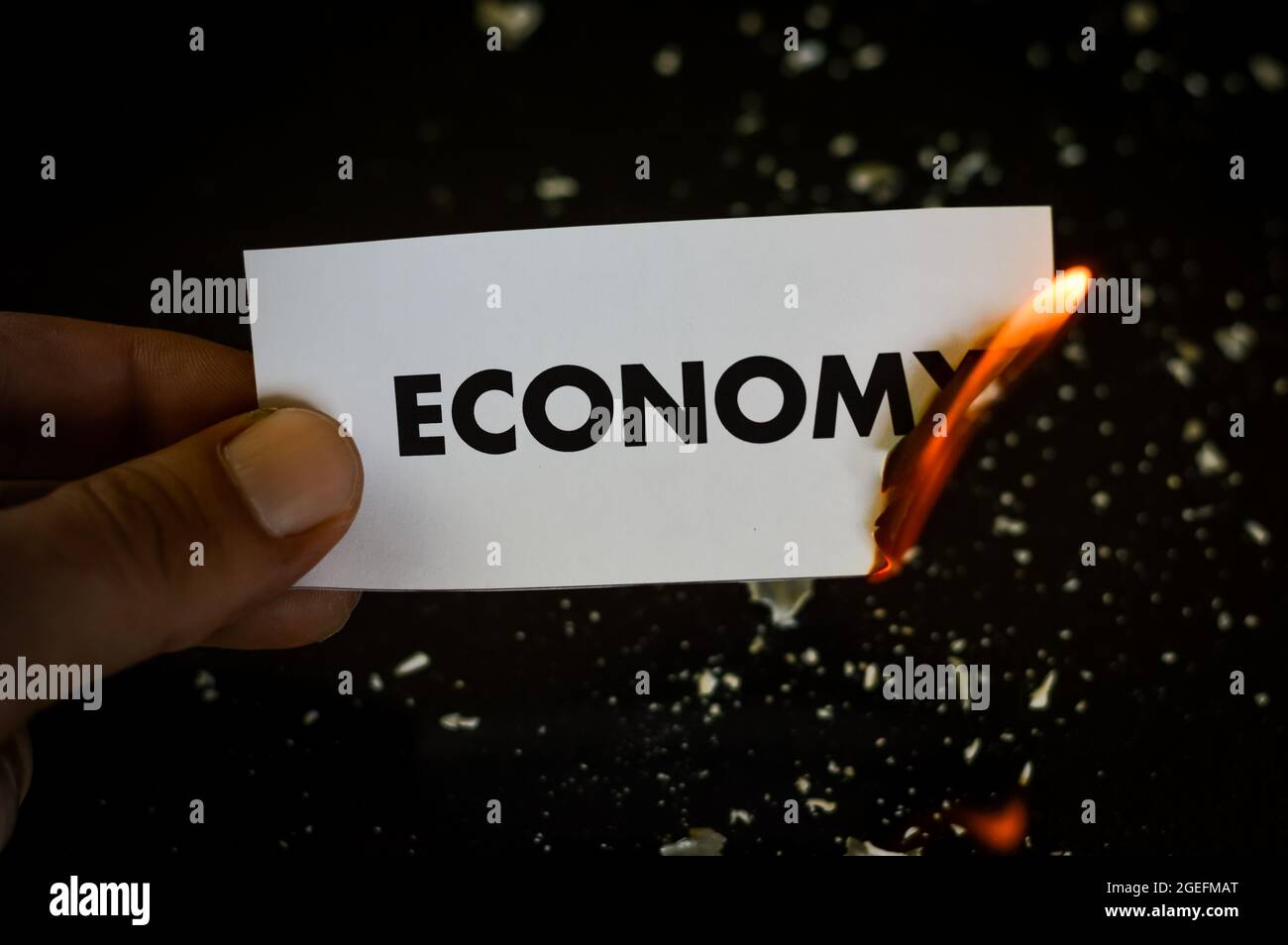 burning economy, human hand holding the word economy written on a paper ...