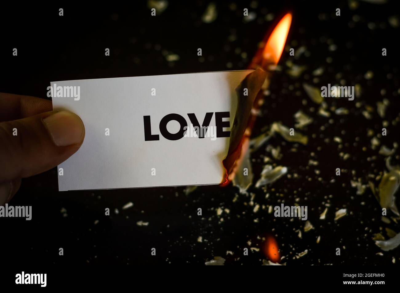 burning love, human hand holding the word love written on a paper ...