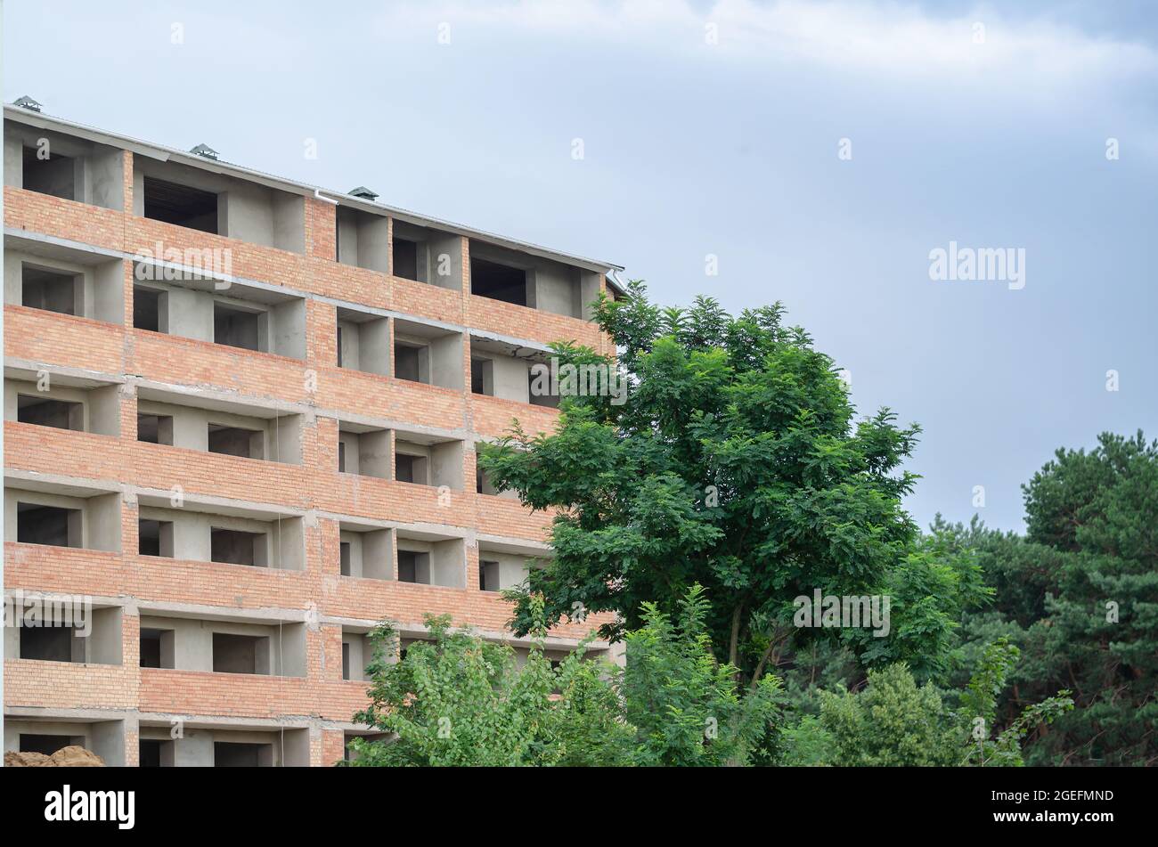Texture of an unfinished building against an overcast sky. A red-brick ...
