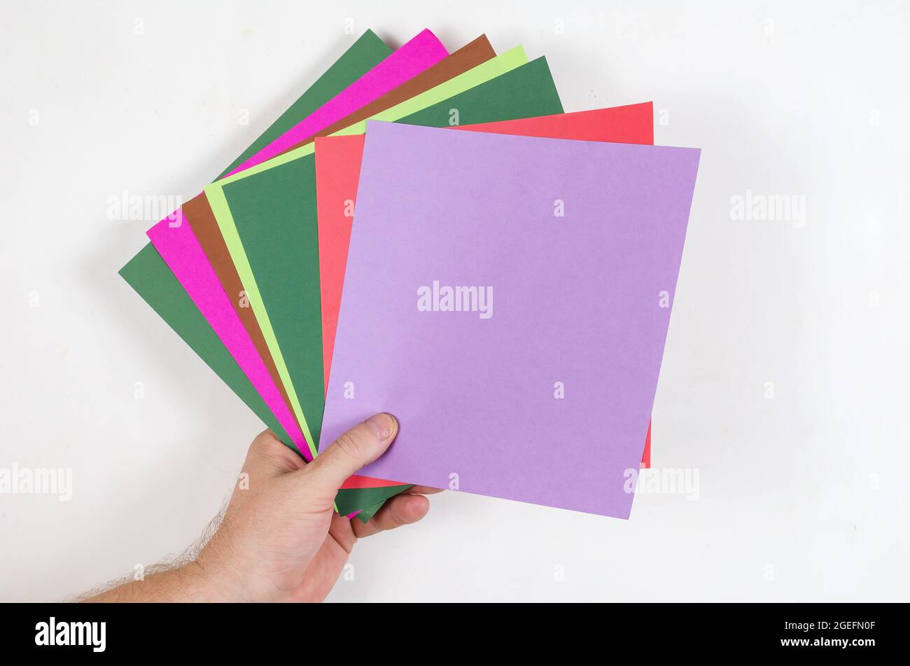 A man holding a colorful paper against a white background. Square ...