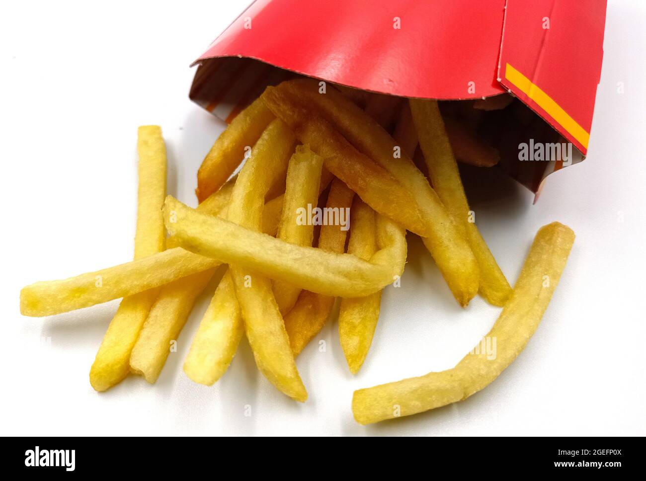 Closeup shot of freshly fried french fries falling out of a red ...