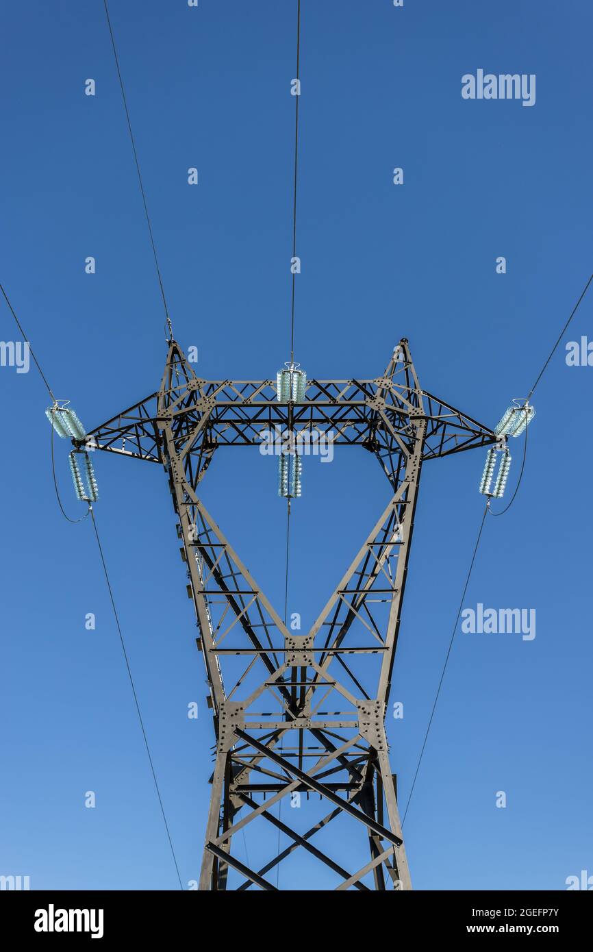 Electricity pylon silhouetted against blue sky background. Copy space ...