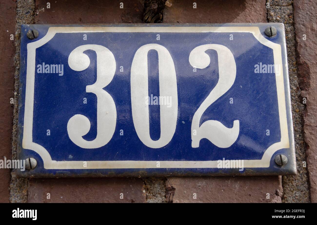 A sign on a wall with the number three hundred two-302 Stock Photo - Alamy