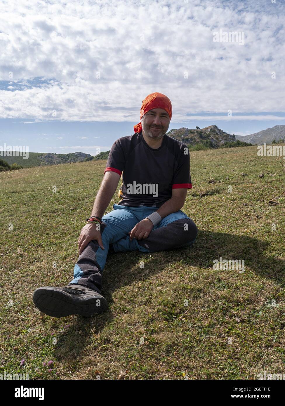 Vertical shot of a Caucasian male sitting on the hill while hiking ...