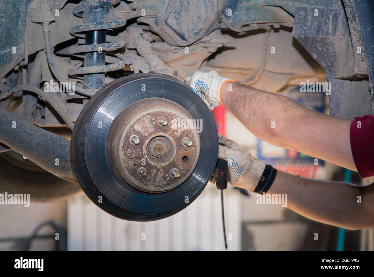 The man's hands detach the worn and rusty rear wheel disc. In the ...