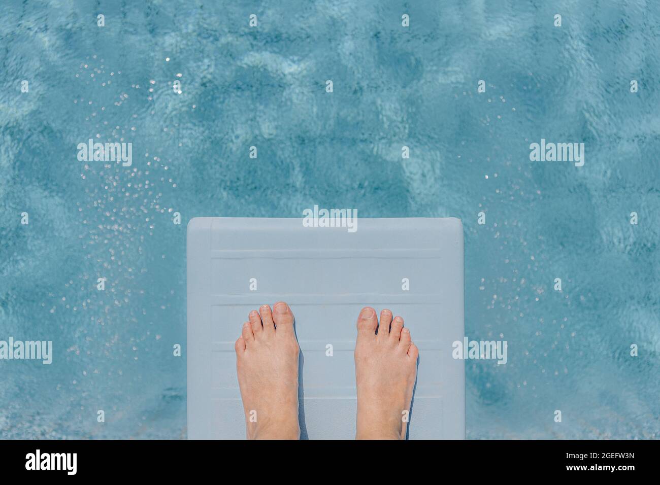 Woman's feet on a diving board in a private swimming pool at home ...