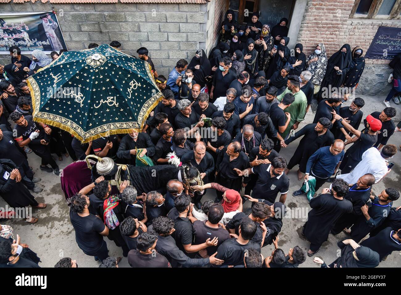Kashmiri Shia Muslims are seen touching a horse (zuljanah) which ...