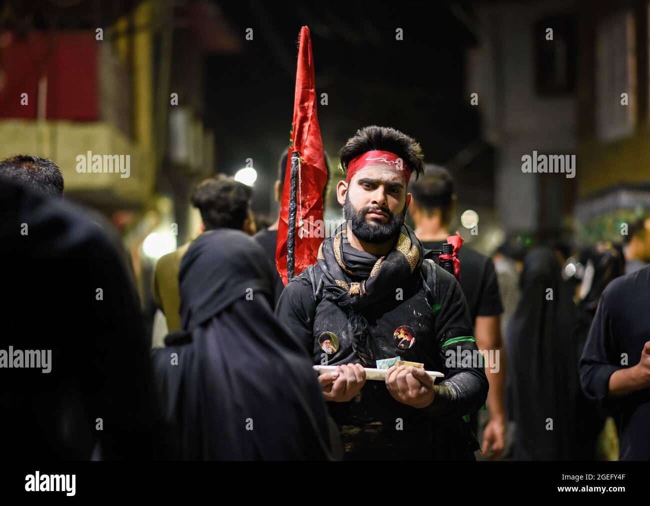 A Kashmiri Shia man hold a plate of soil taken from the holy Iraqi Shia ...