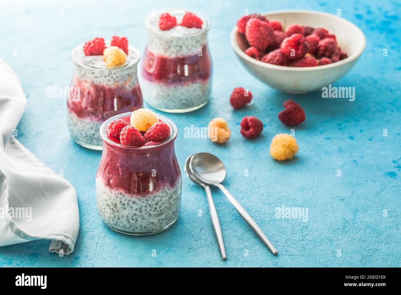glass jars with chia pudding with raspberry and jam. Bowl of raspberry ...