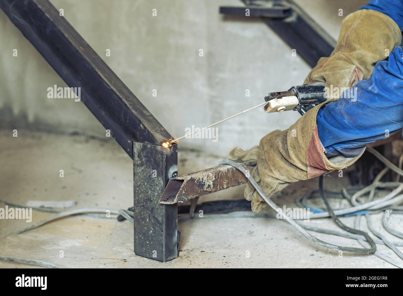 Man welder assembles a metal staircase structure in a residential ...