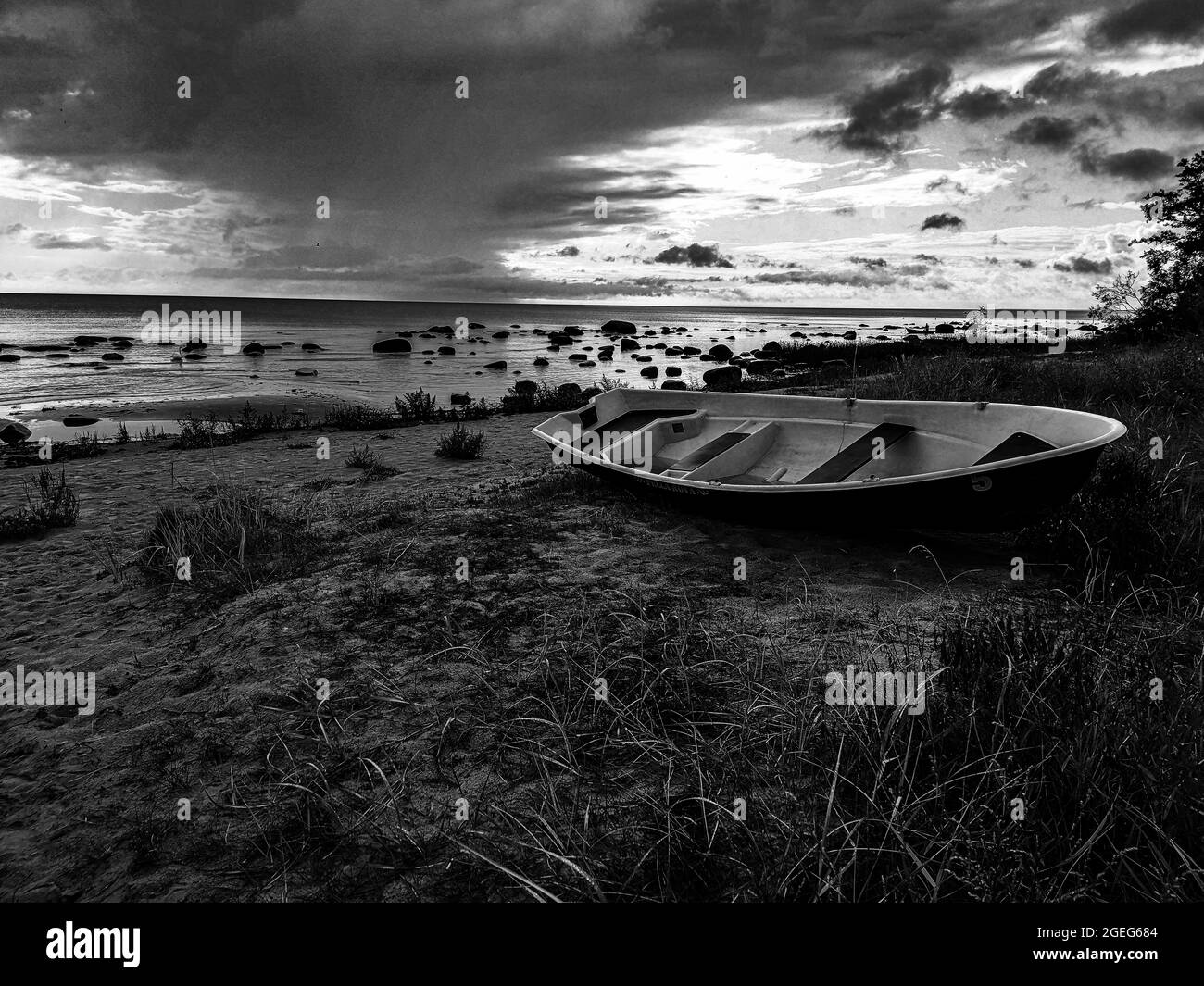 Ocean with a boat on the beach under a gloomy sky Stock Photo - Alamy