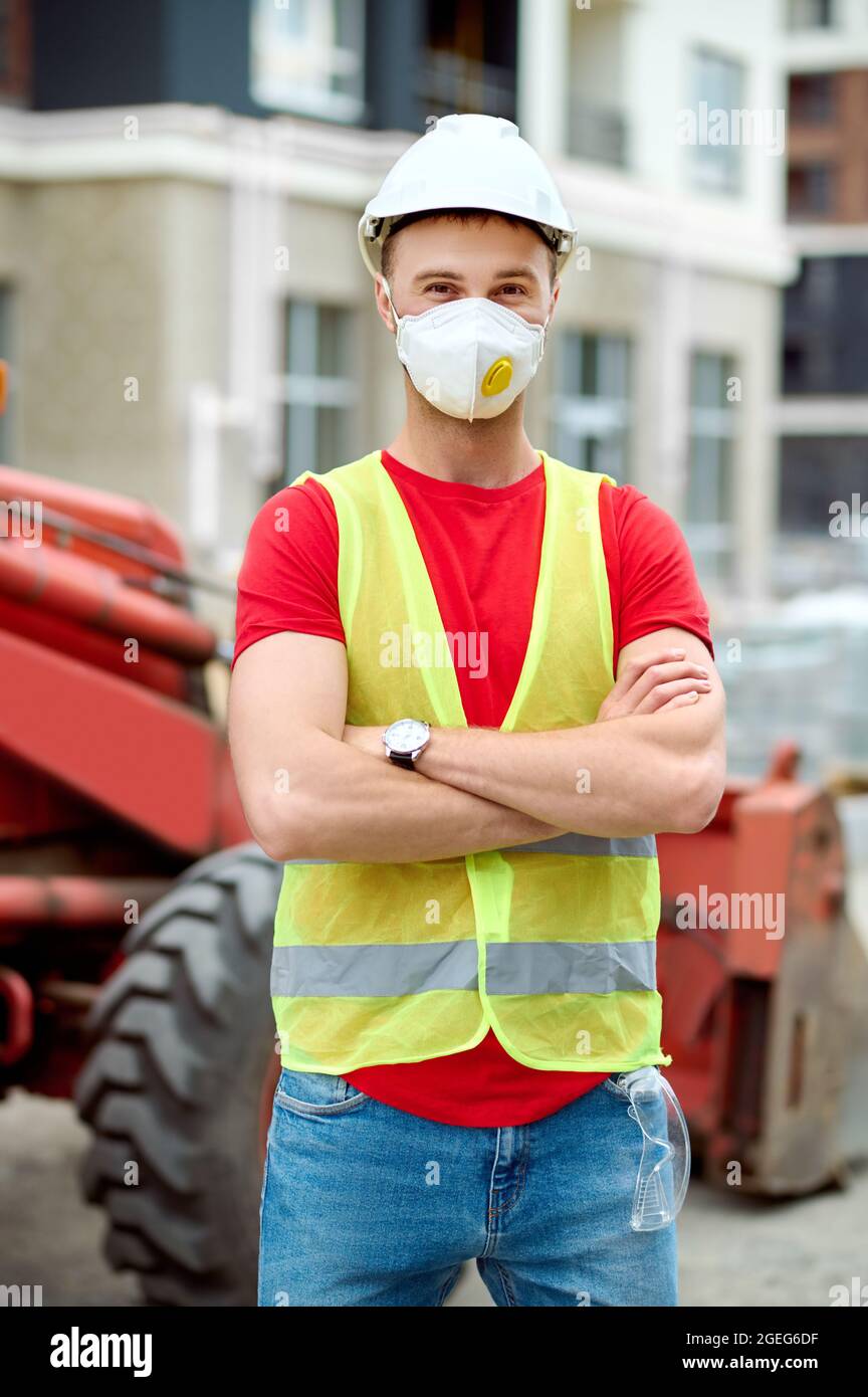 Worker in a safety vest standing by a built structure Stock Photo - Alamy