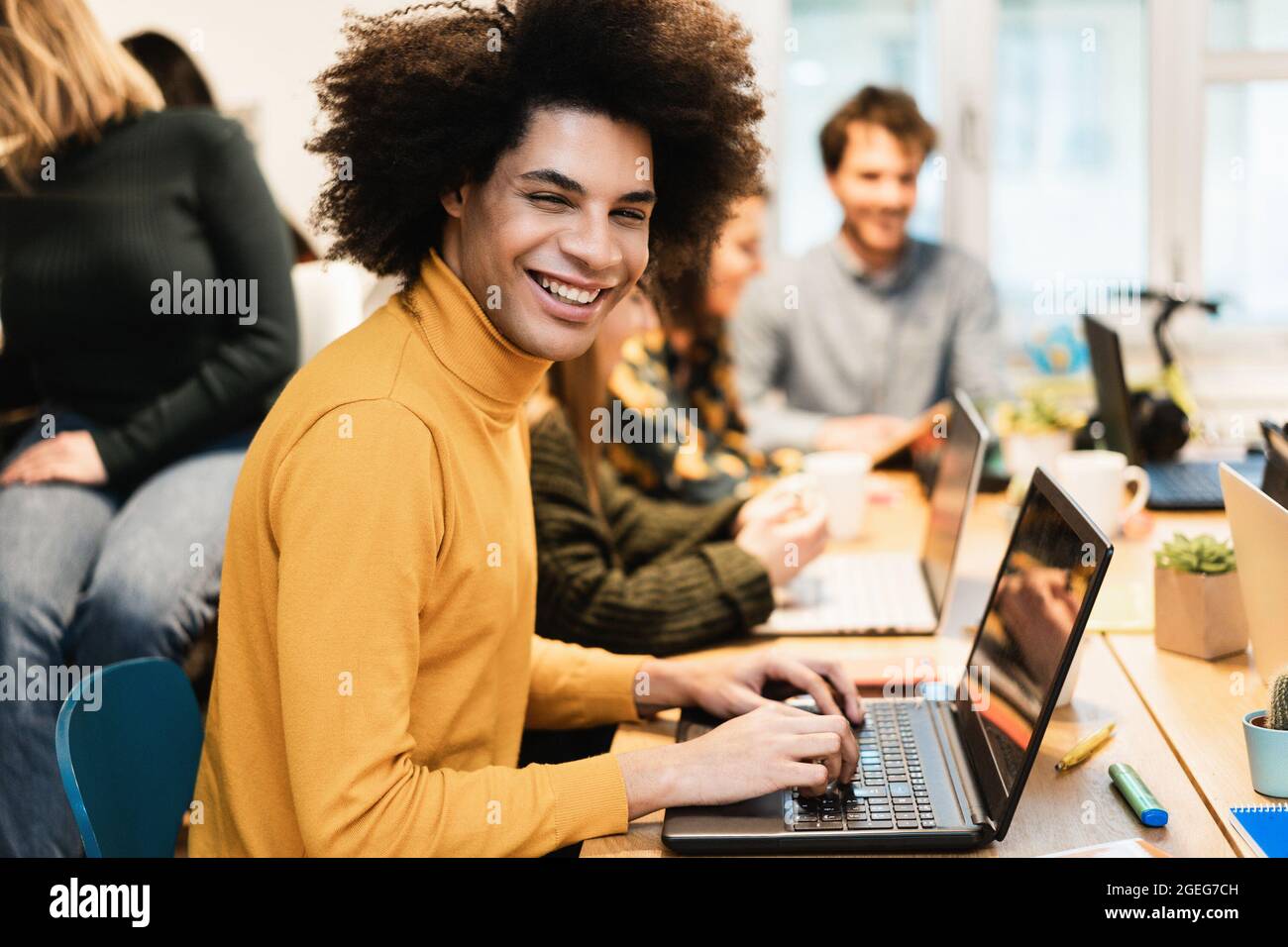 Young african guy looking at camera while working inside coworking ...