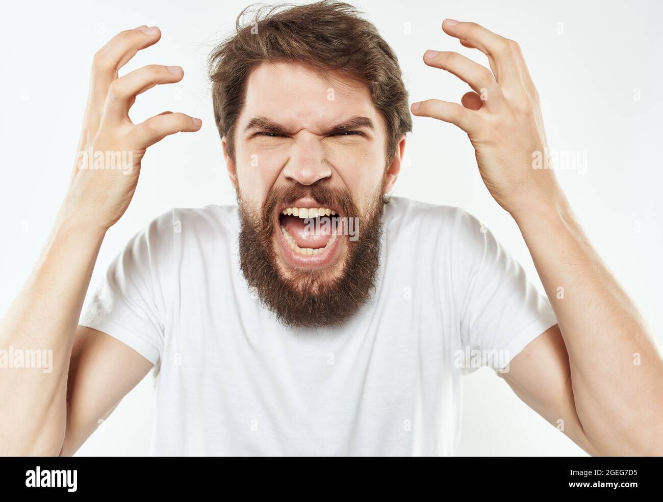 emotional man in a white t-shirt irritated facial expression light ...