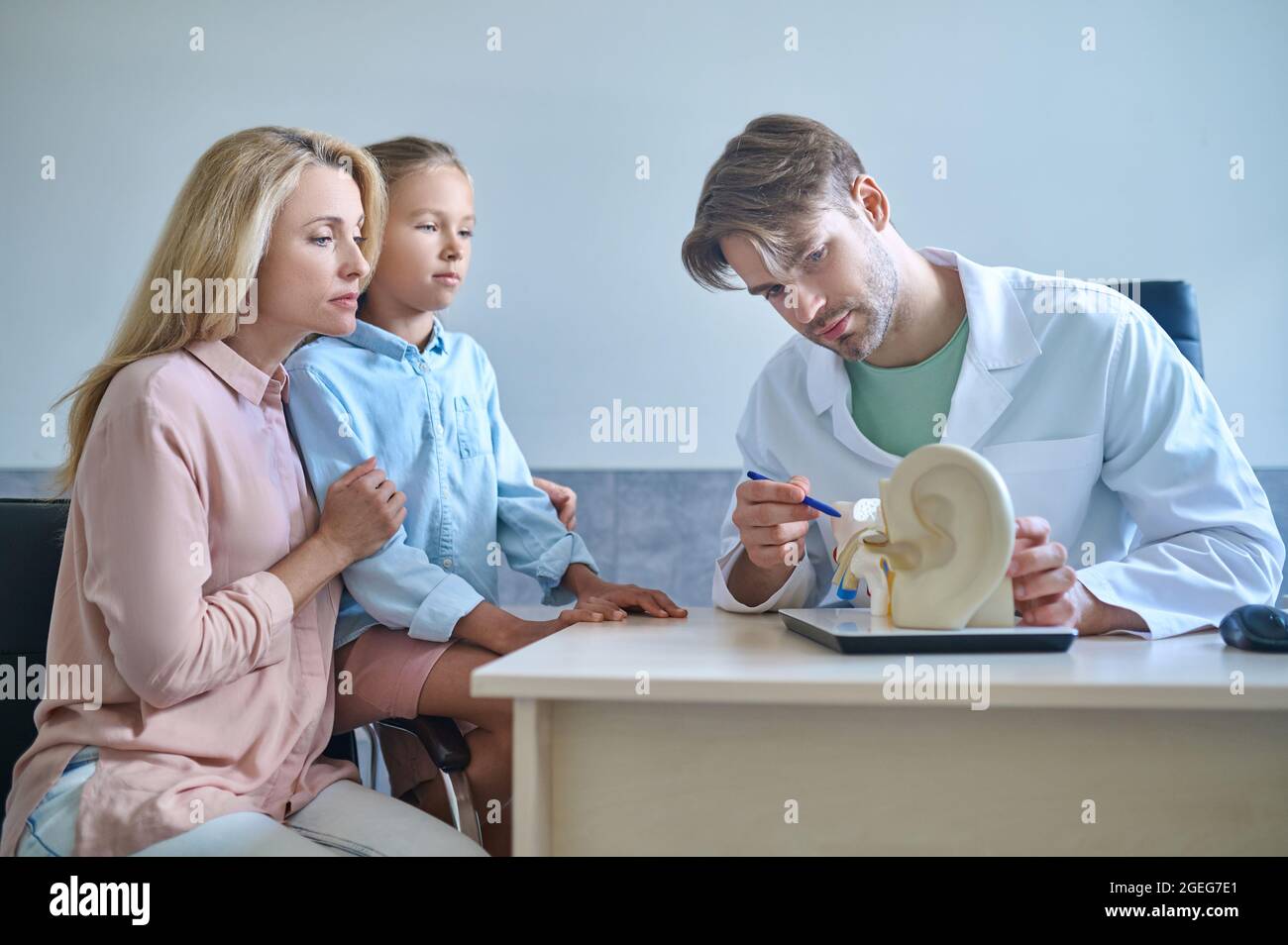 Audiologist showing the auditory system demonstration model to his ...