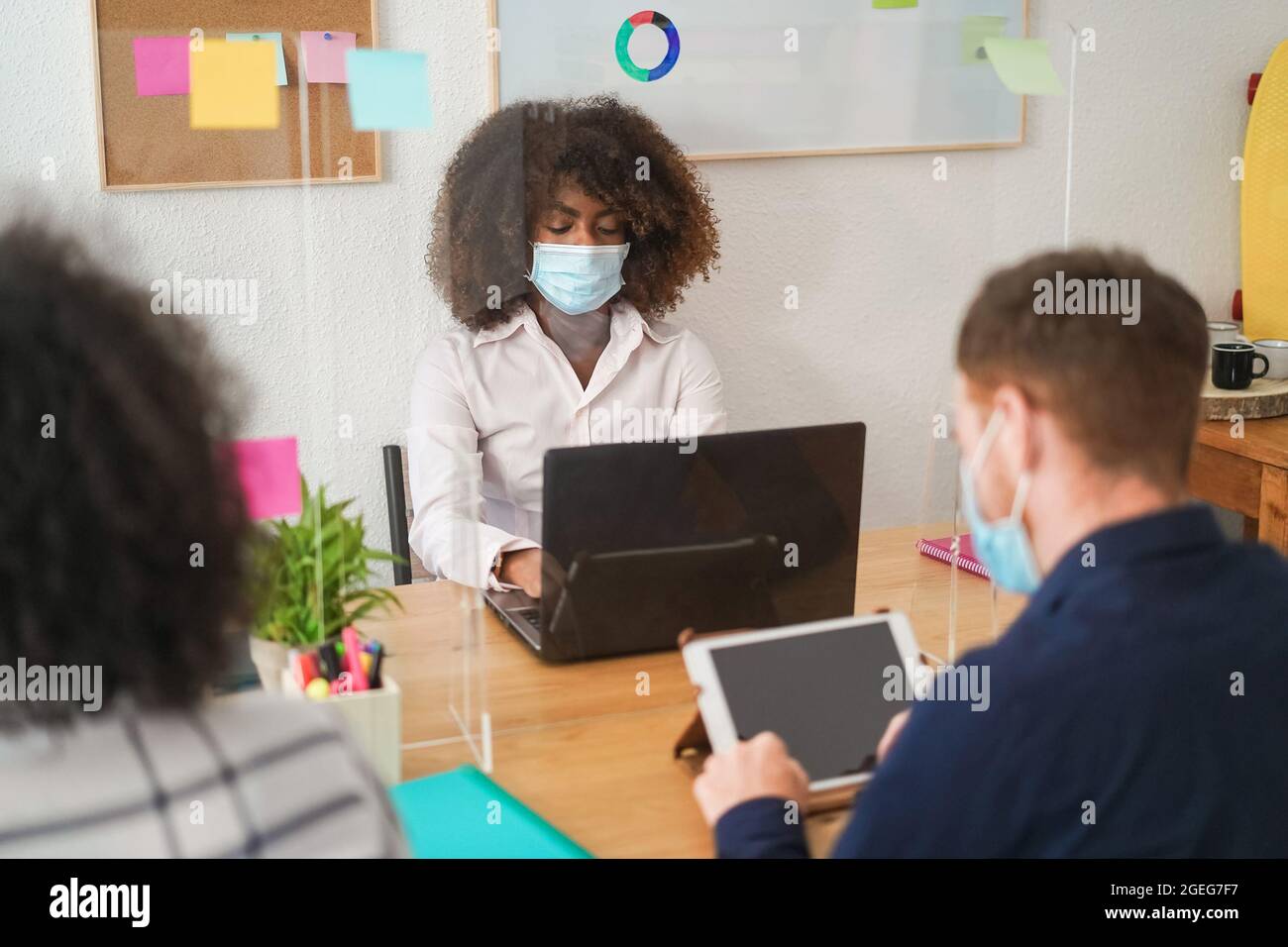Diverse young people working inside coworking office while wearing ...