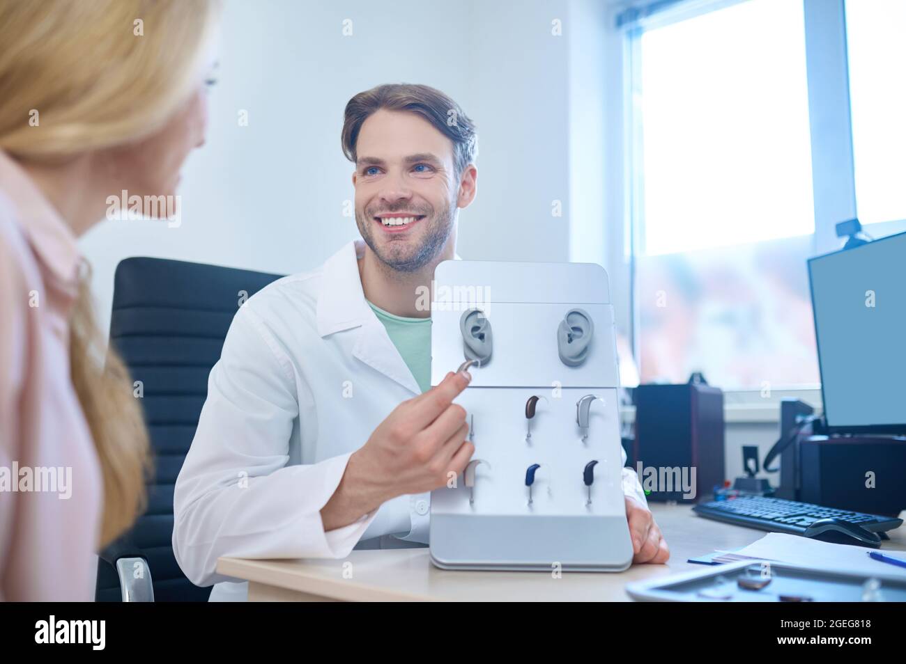 Friendly doctor offering different deaf aids to his a patient Stock ...
