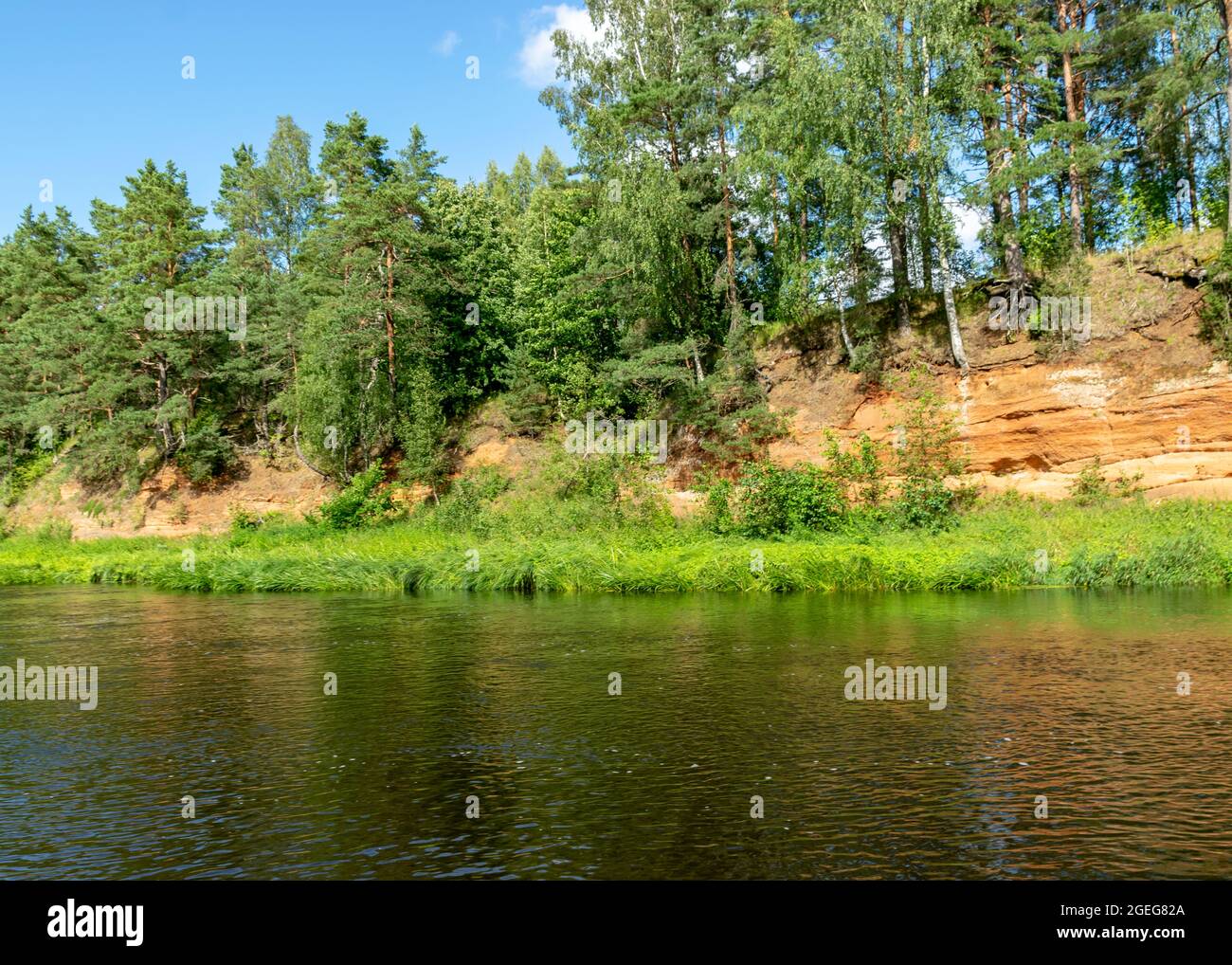colorful summer landscape from the river, with red, sandstone cliffs on ...