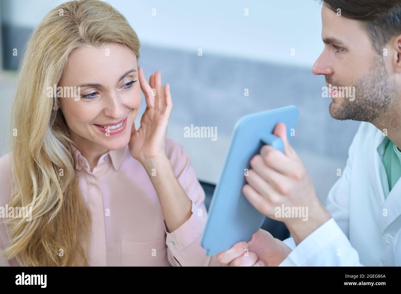 Happy female patient admiring her reflection in the handglass Stock ...