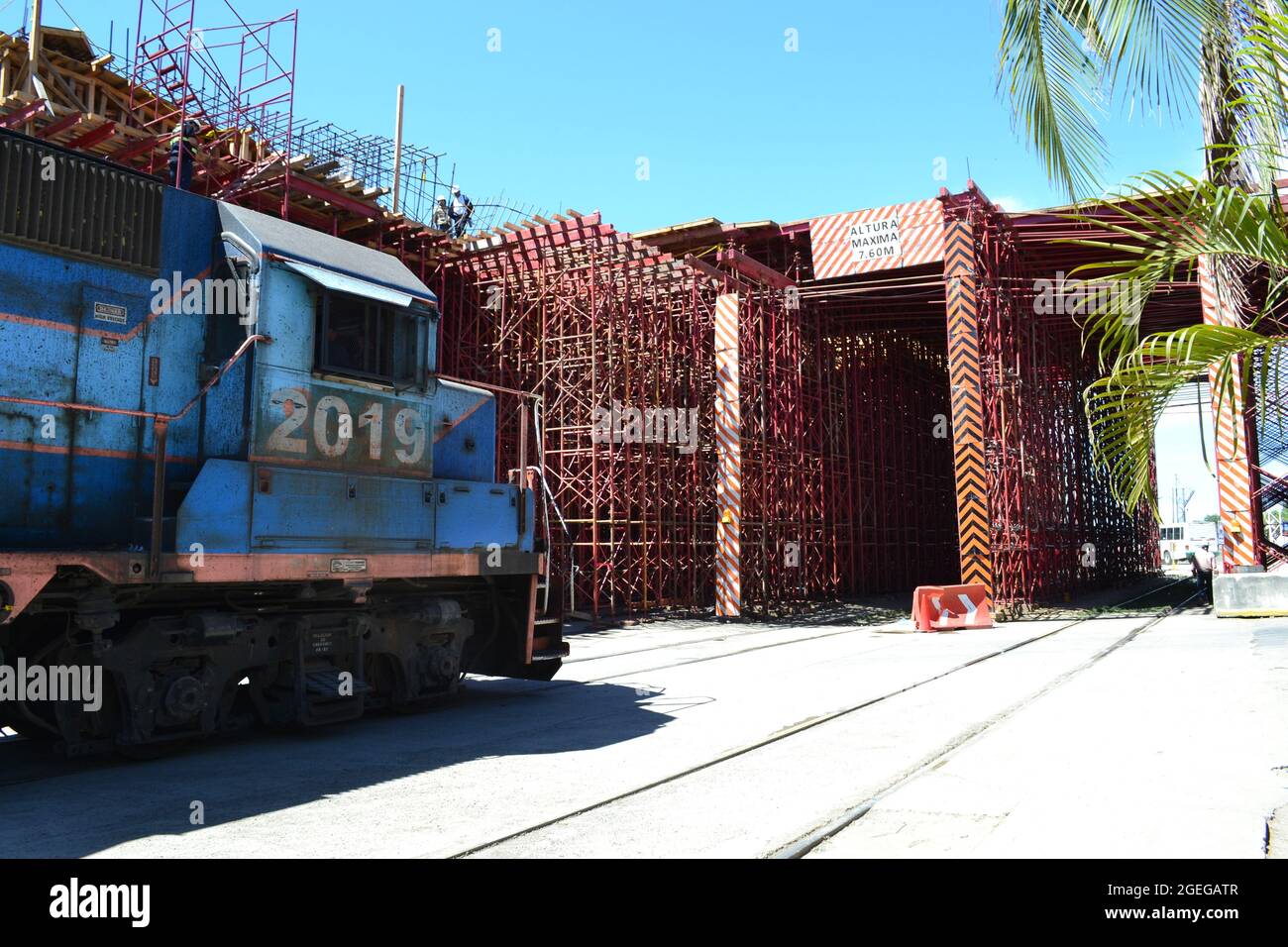 blue train passing through a tunnel built with construction scaffolding ...