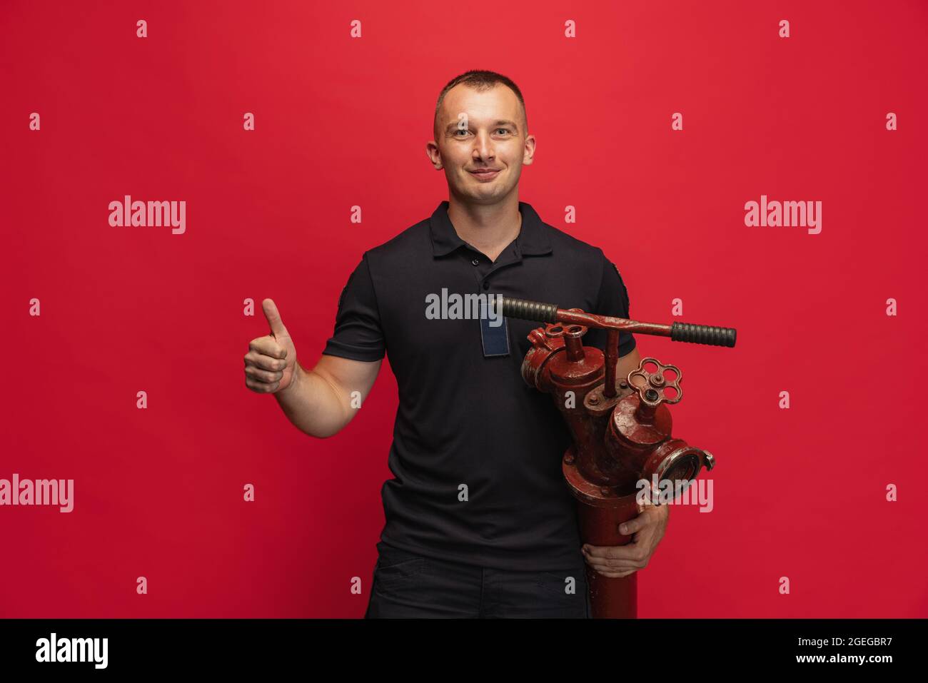 Portrait of young smiling man with fire hydrant posing over red ...