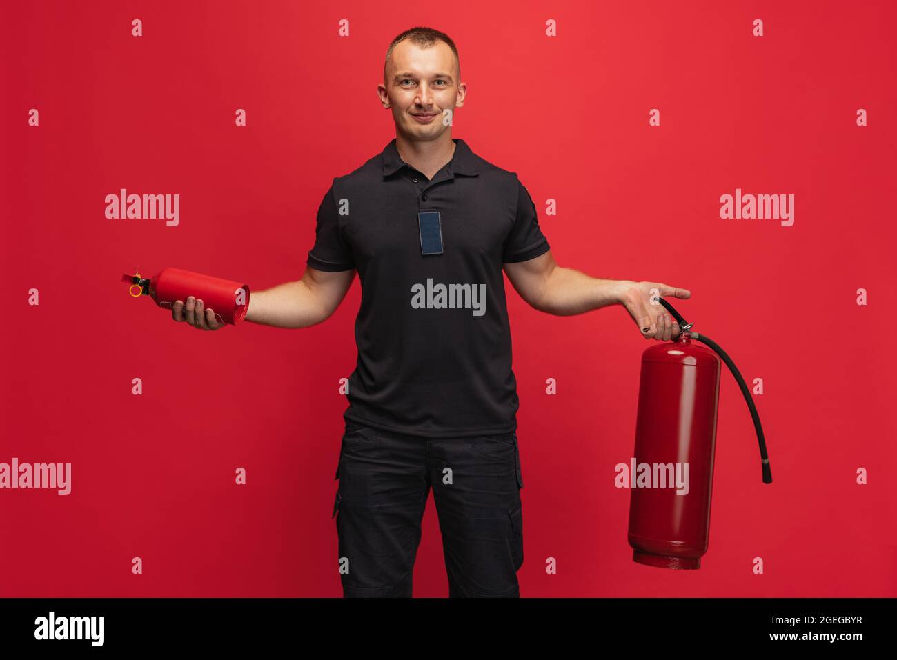 Fire safety. Portrait of young smiling man with extinguishers posing ...