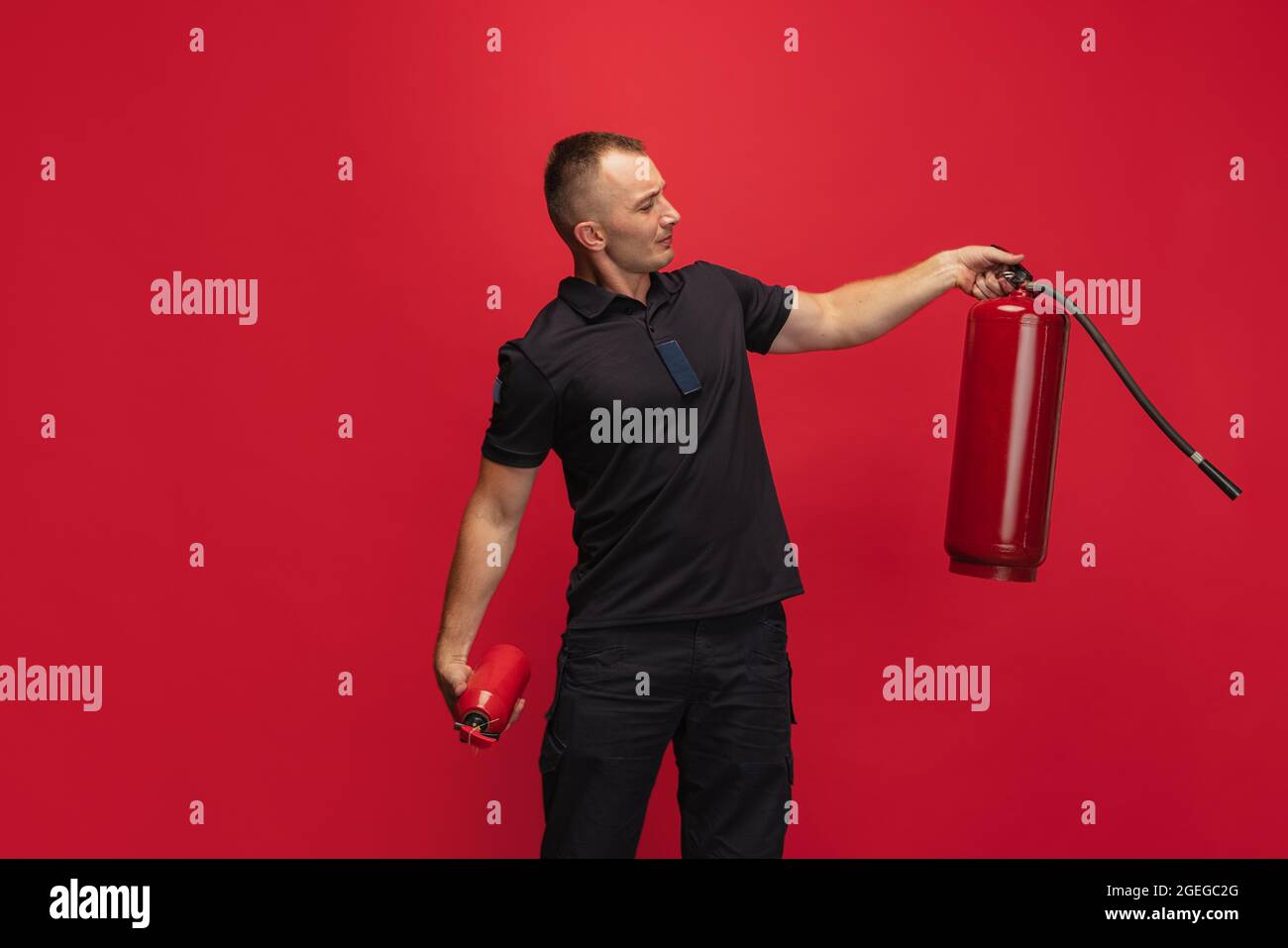 Fire safety. Portrait of young smiling man with extinguishers posing ...