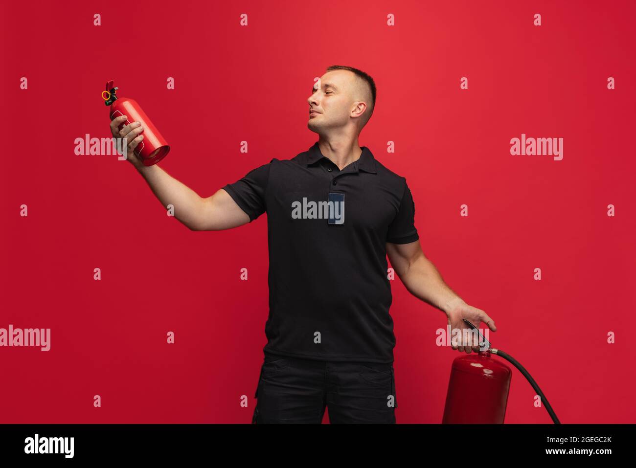 Fire safety. Portrait of young smiling man with extinguishers posing ...
