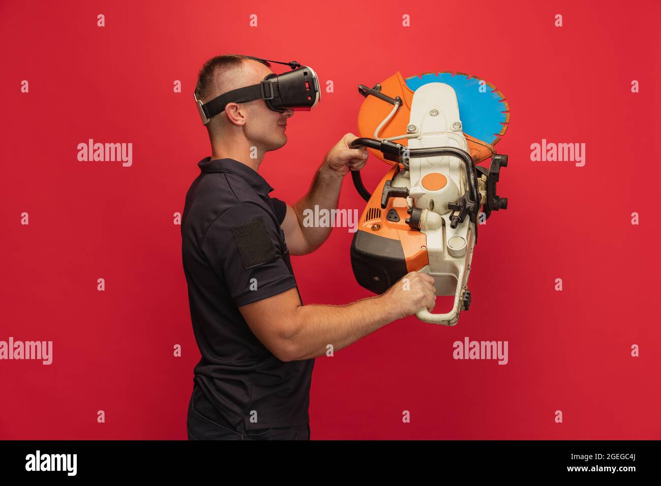 One young cheerful caucasian man in VR glasses with electric saw posing ...