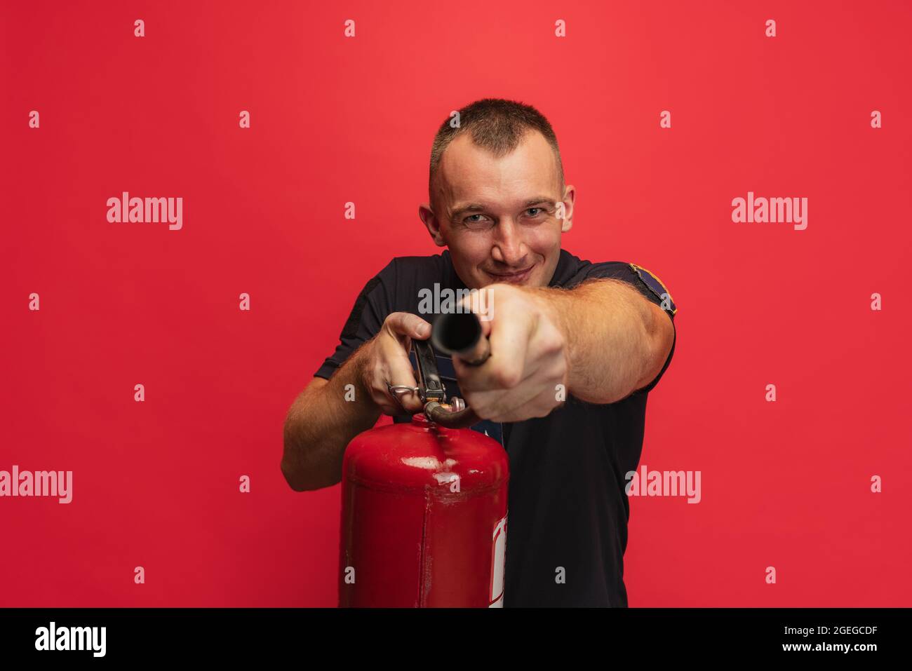 Fire safety. Portrait of young smiling man with extinguisher posing ...