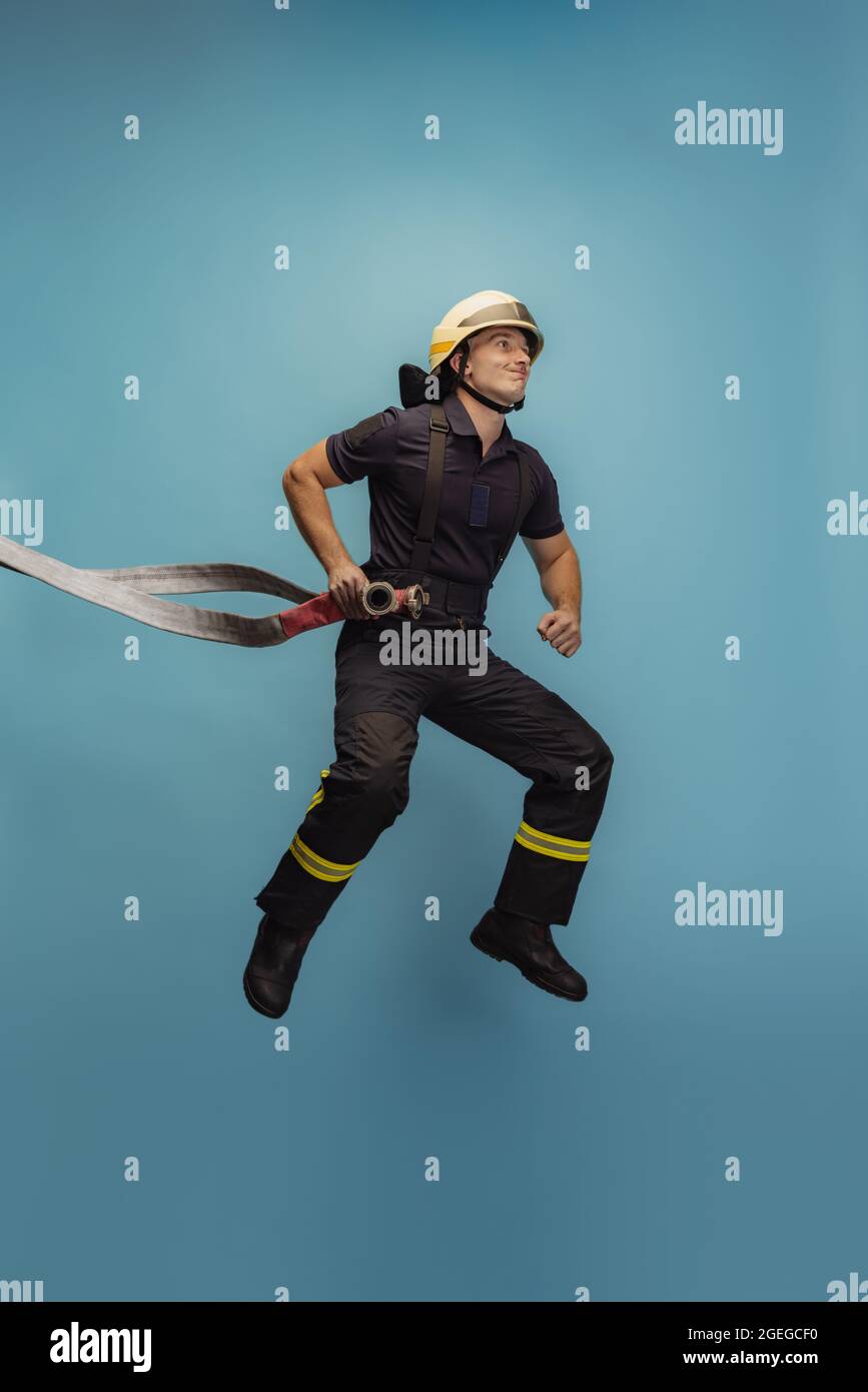 Vertical portrait of young male fireman in uniform posing with water ...