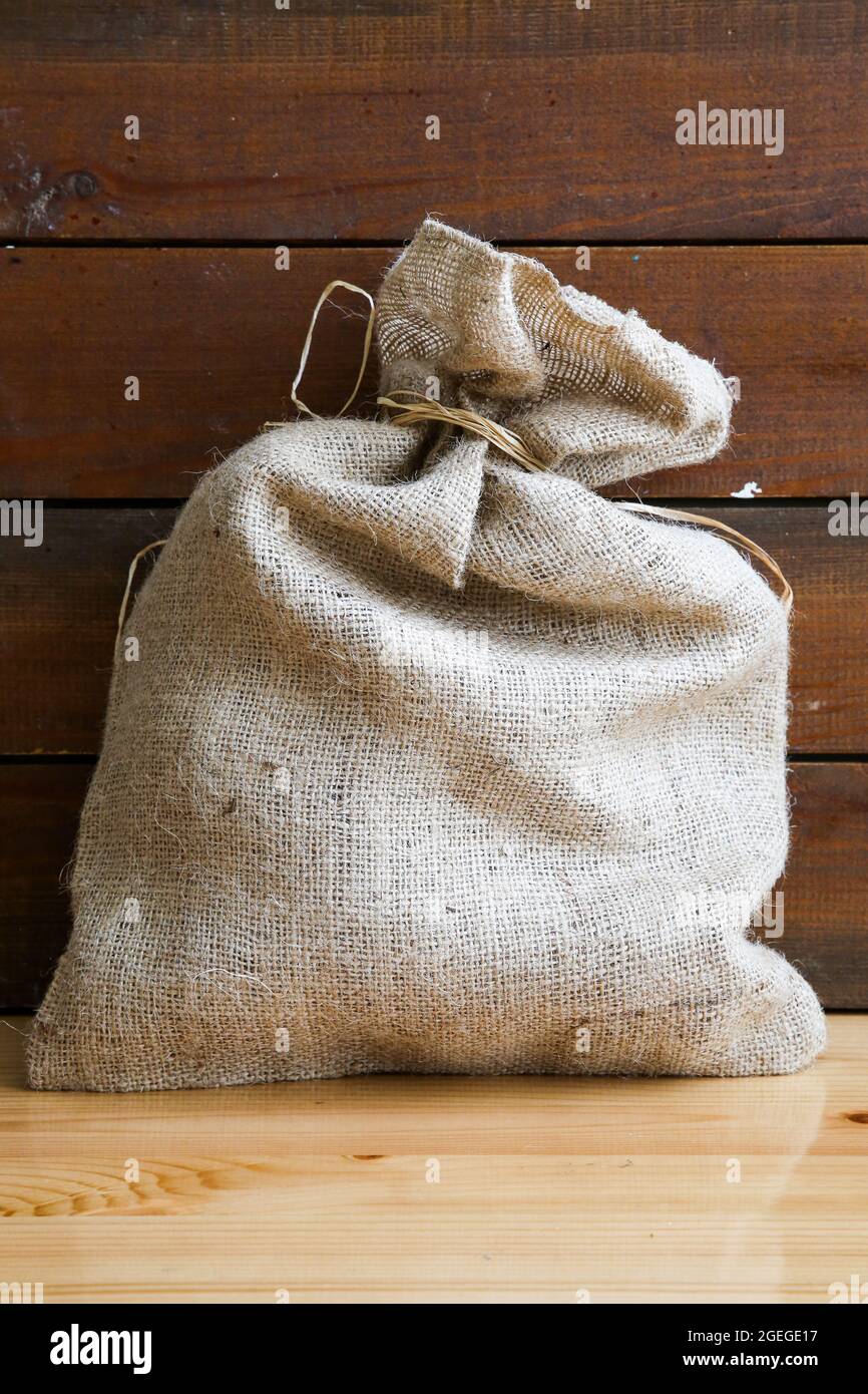 a tied linen sack in front of a wooden backdrop Stock Photo - Alamy