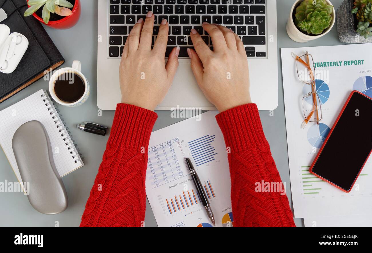 Woman hands wearing red sweater typing on laptop near reports, coffee ...