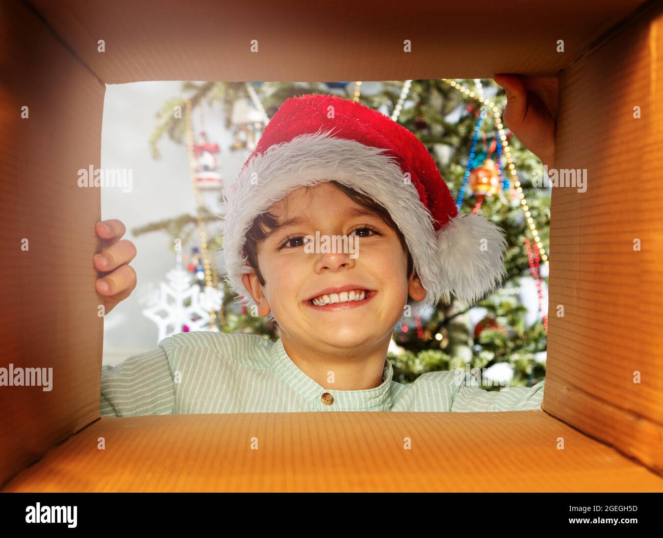 Child looks in present box wearing Santa hat Stock Photo - Alamy
