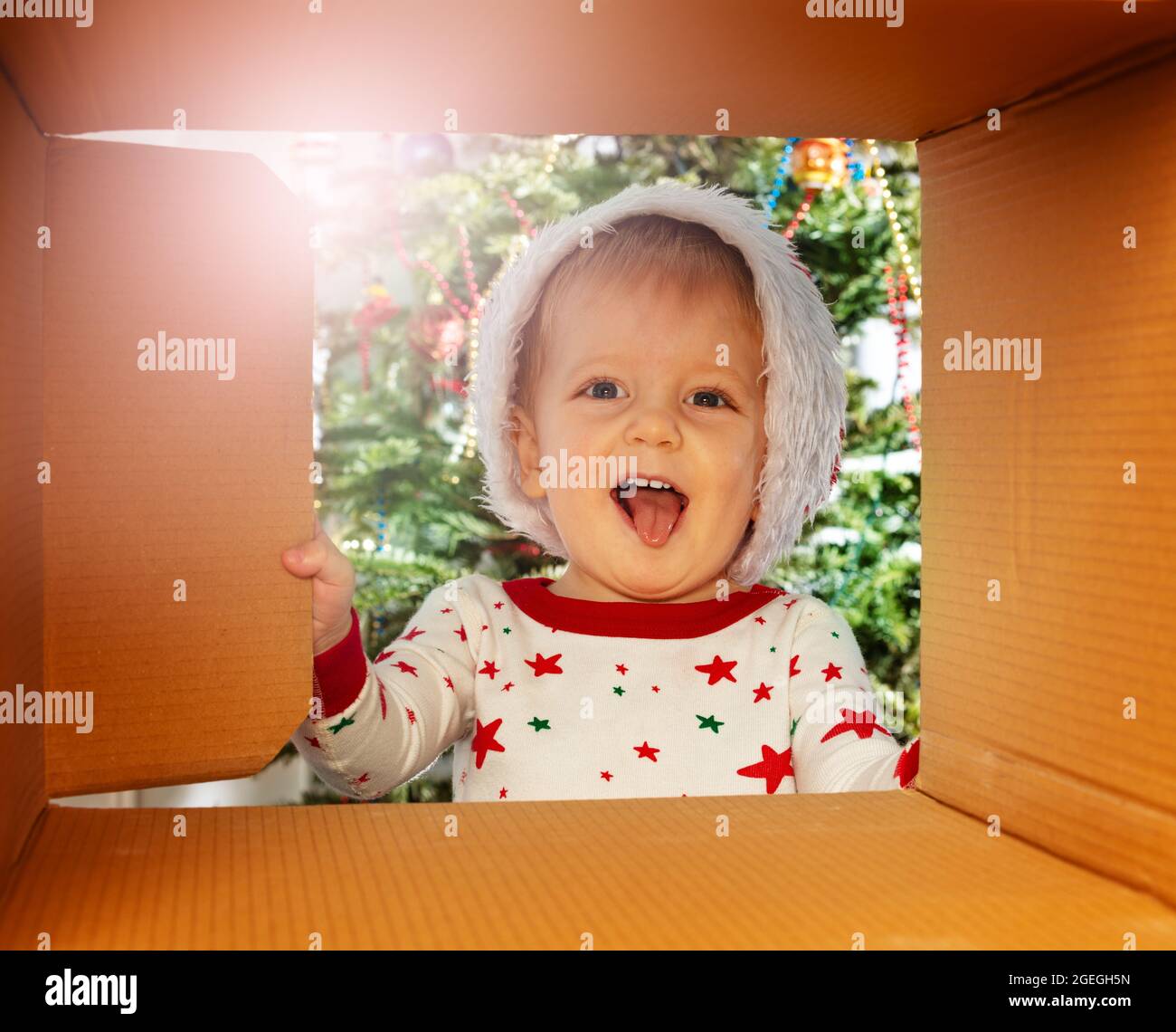 Boy look inside present box wearing Christmas hat Stock Photo - Alamy