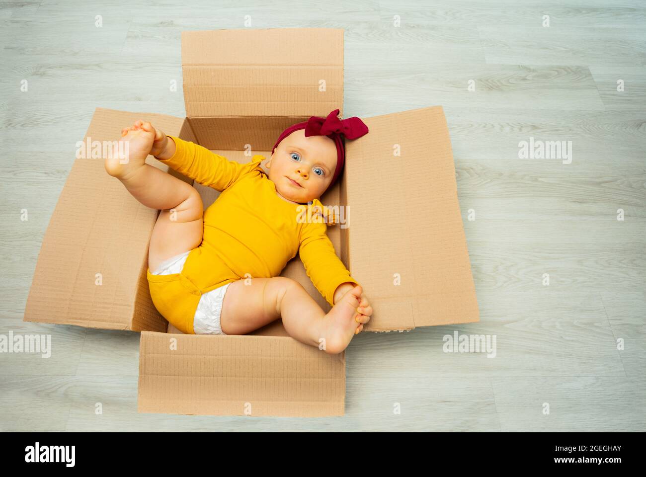 Baby girl in open cardboard box on the floor Stock Photo - Alamy