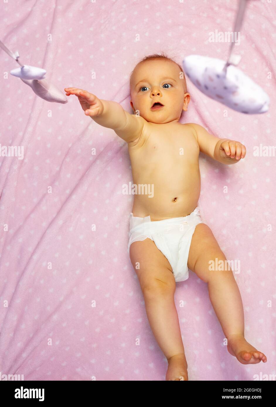 Baby girl reach with hand mobile toys from above Stock Photo - Alamy