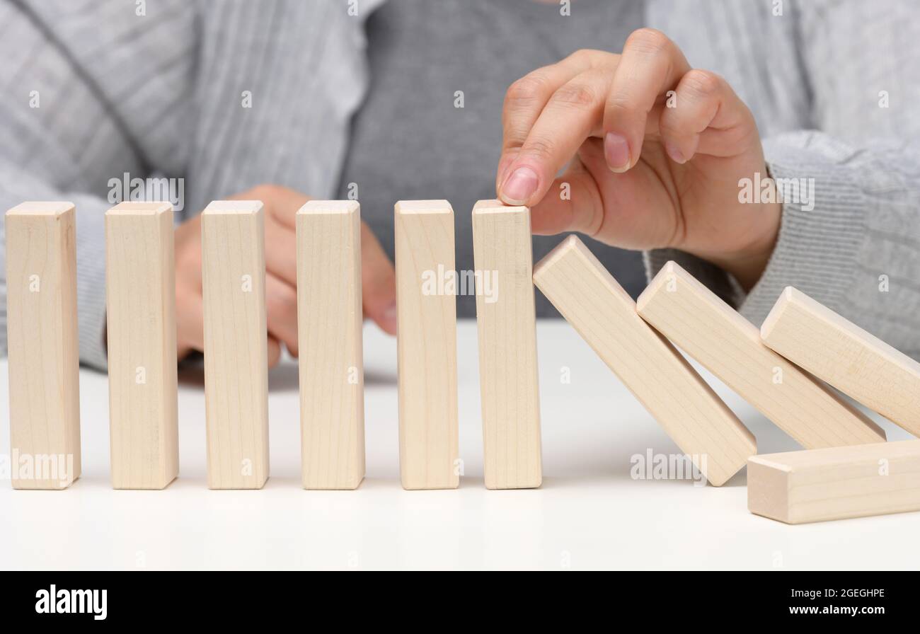 hand stops the fall of wooden blocks on a white background. Concept of ...