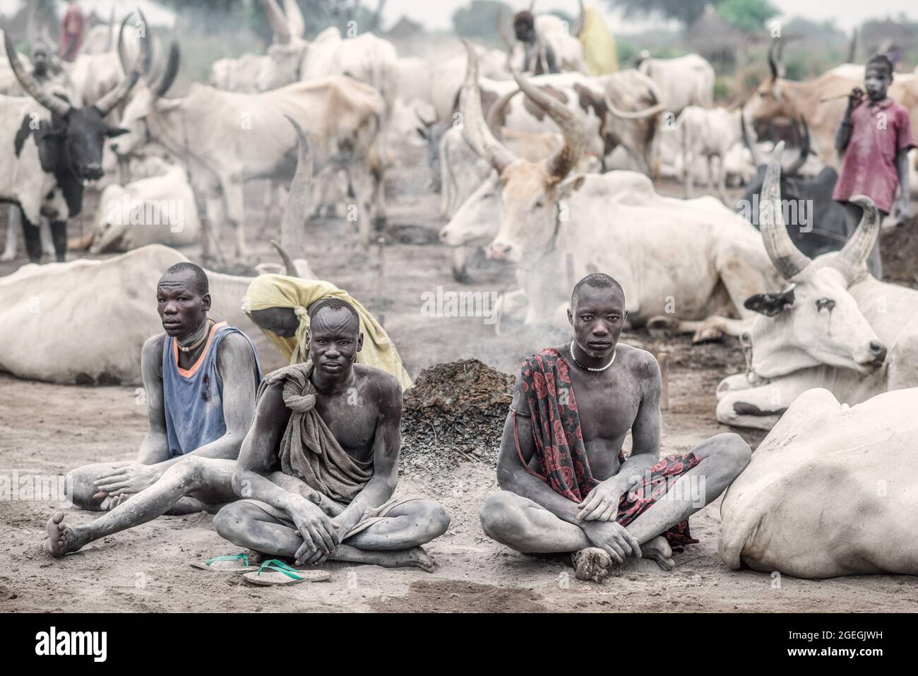 Three tribe members looked into the camera as they sat by a burning ...