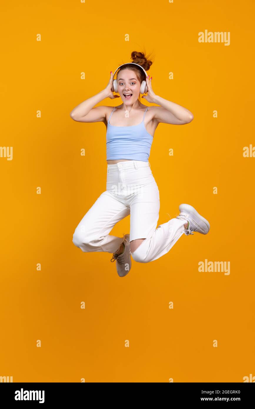 Vertical image of young cute girl jumping isolated on yellow studio ...